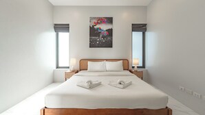 Quarto de hotel moderno com uma cama grande, duas mesas de cabeceira com abajures, uma obra de arte na parede e uma janela com vista.