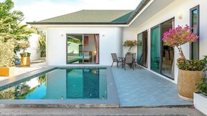 Uma casa moderna com piscina, um alpendre com móveis de exterior e uma janela grande.