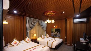Quarto de hotel com duas camas, uma escrivaninha, um computador e um quadro na parede.