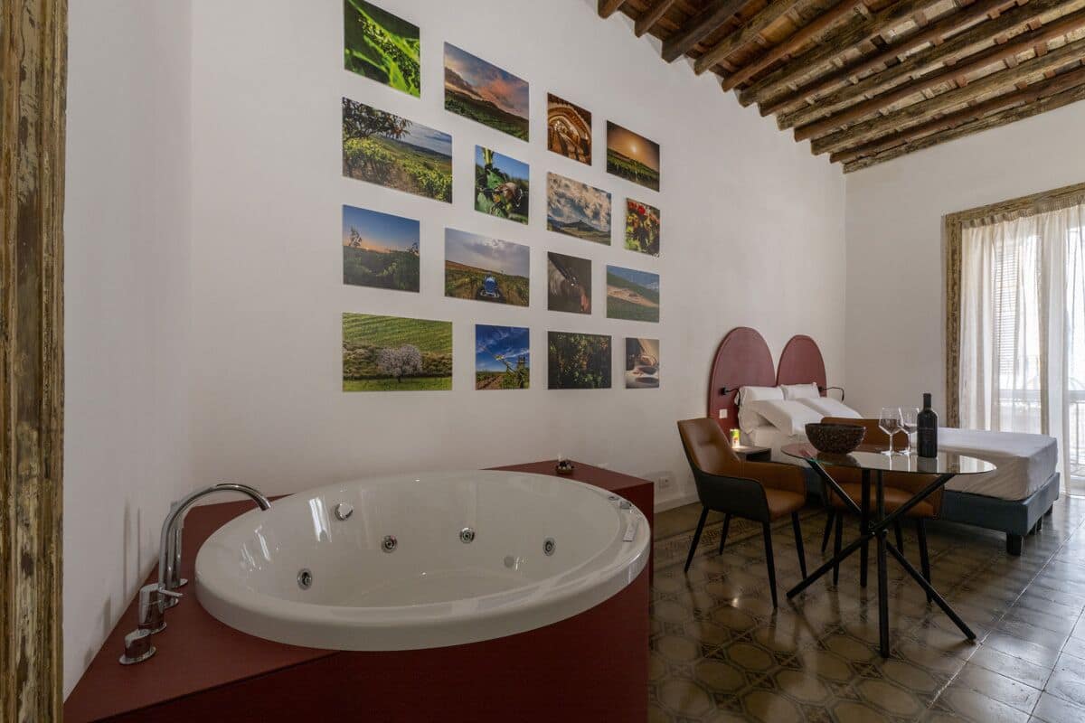 Um banheiro com uma banheira grande, uma sala de jantar com mesa e cadeiras, e uma cama com janela.