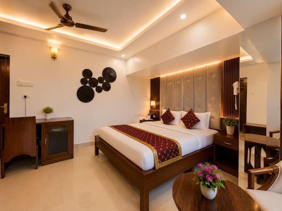 Quarto de hotel moderno com uma cama grande, mesas de cabeceira, uma escrivaninha e uma cadeira.