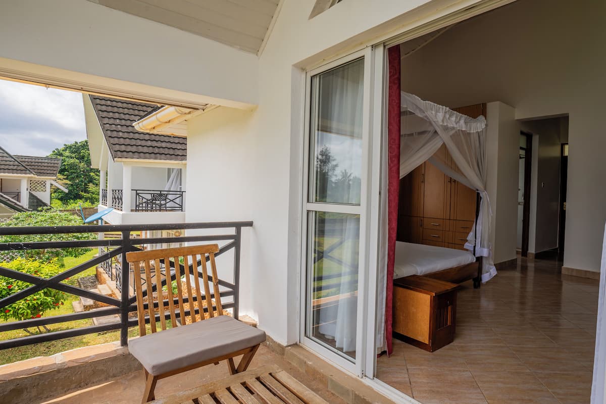 Uma varanda com um banco de madeira, uma cama com dossel e vista para os arredores.