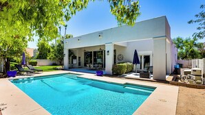 Uma casa moderna com piscina, mobiliário de jardim e área externa coberta.
