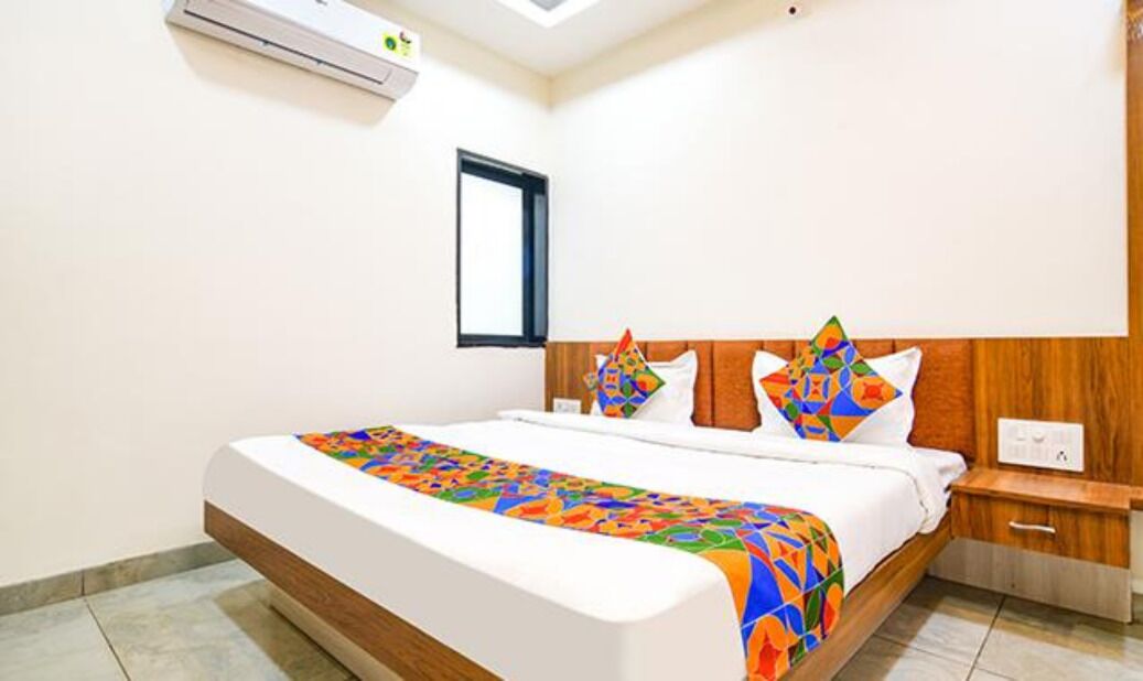 Quarto com cama, mesa de cabeceira, janela e ar condicionado.