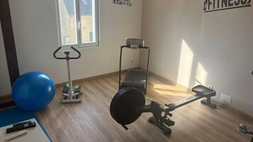 Uma academia com equipamentos de ginástica, uma bola de exercícios azul e adesivos motivacionais na parede.