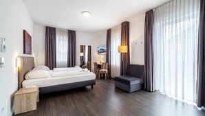Quarto de hotel moderno com uma cama grande, uma escrivaninha e uma cadeira.