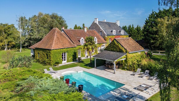 Uma casa grande com piscina, varanda coberta e jardim exuberante.