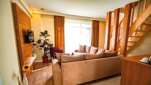 Uma sala de estar com sofá, mesa de centro, planta e escada.