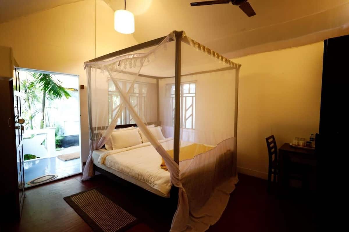 Quarto com cama de dossel, uma mesa de jantar e um ventilador de teto.