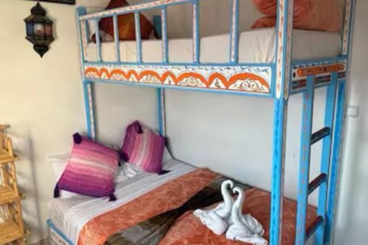 Uma cama beliche com dois níveis, cada um com travesseiros e cobertor.