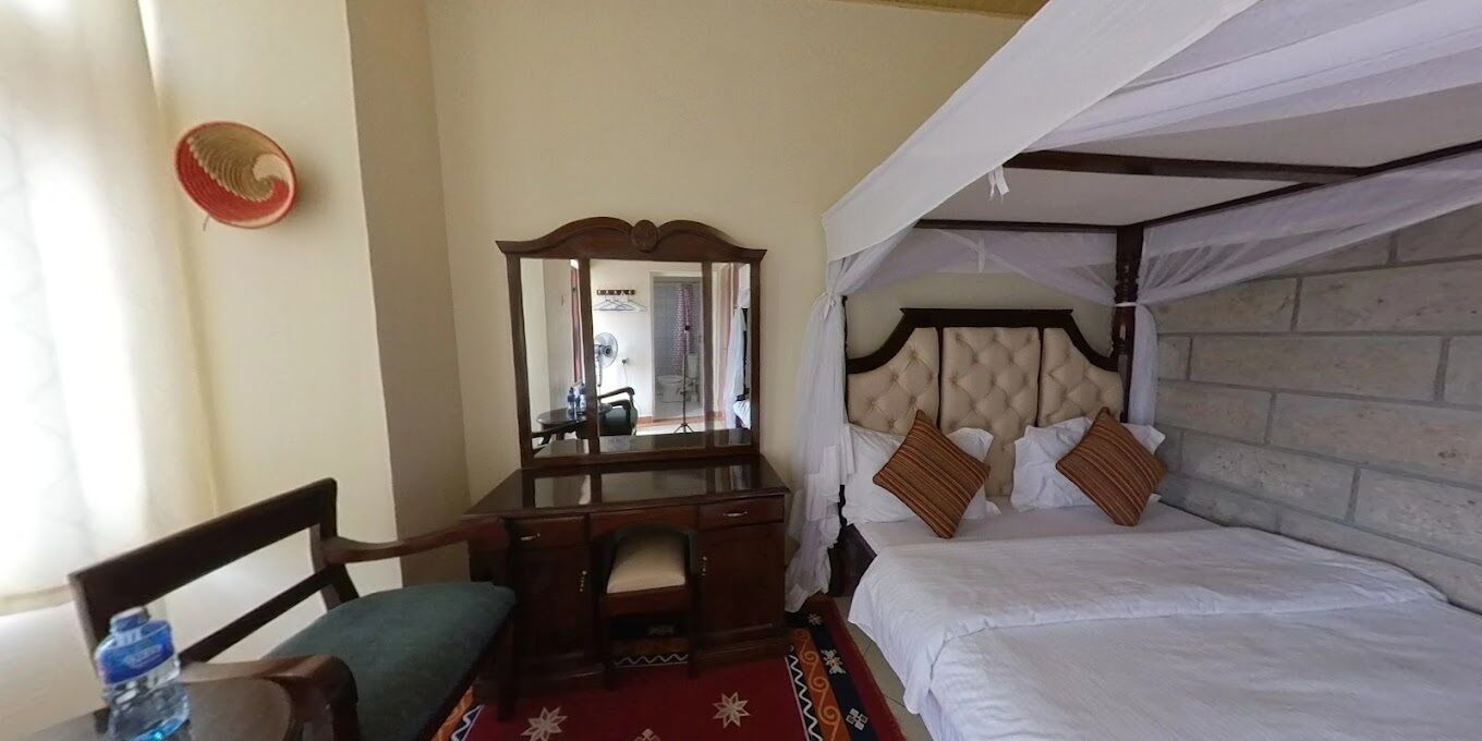 Quarto com cama, cómoda de madeira, espelho e dossel.