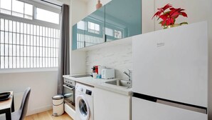 Uma cozinha compacta com máquina de lavar, pia e geladeira.