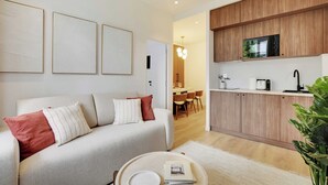 Uma sala de estar moderna com sofá, área de jantar e cozinha com armários de madeira e televisão.