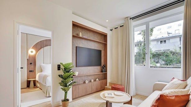 Uma sala de estar moderna com televisão de tela plana, um sofá, uma mesa de centro e um vaso com planta.