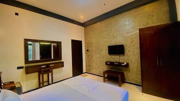 Quarto de hotel com uma cama grande, televisão fixada na parede e um guarda-roupa.