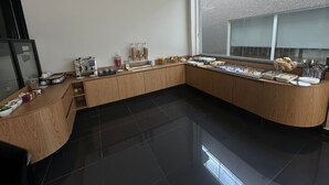 Uma cozinha moderna com bancada curva de madeira, uma máquina de café e diversos alimentos expostos no balcão.