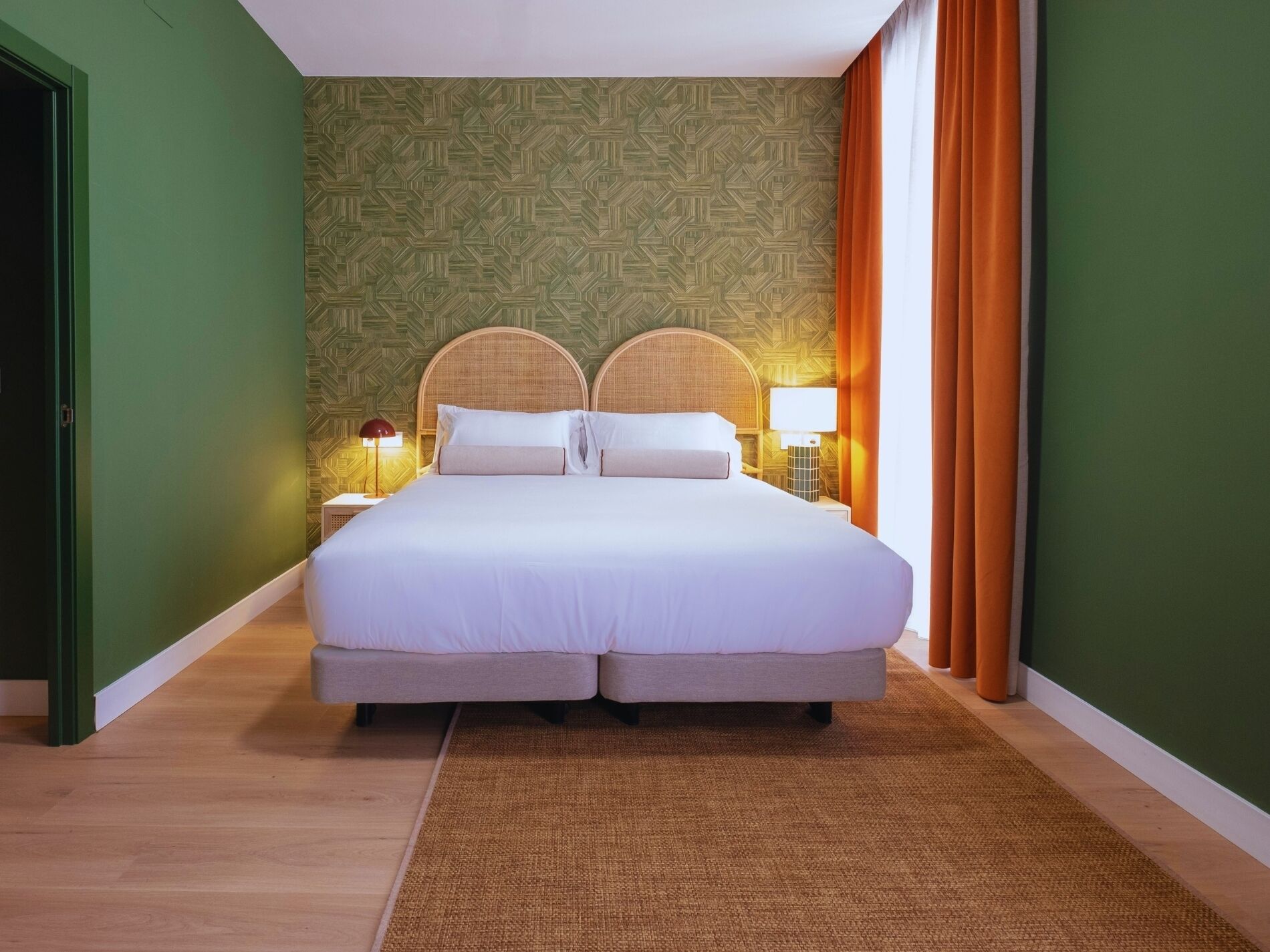 Quarto de hotel com uma cama grande, duas mesas de cabeceira e um papel de parede estampado.