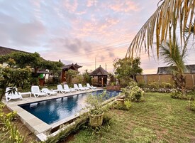 Piscina com espreguiçadeiras, rodeada por vegetação e arquitetura tradicional.
