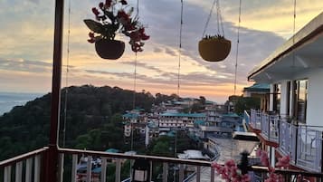 Varanda com jardineiras floridas e vista para uma vila no topo da colina.