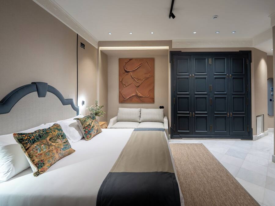 Quarto de hotel moderno com uma cama grande, um painel decorativo e um guarda-roupa escuro.