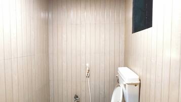 Um banheiro pequeno, com azulejos, que inclui vaso sanitário, chuveiro e janela.
