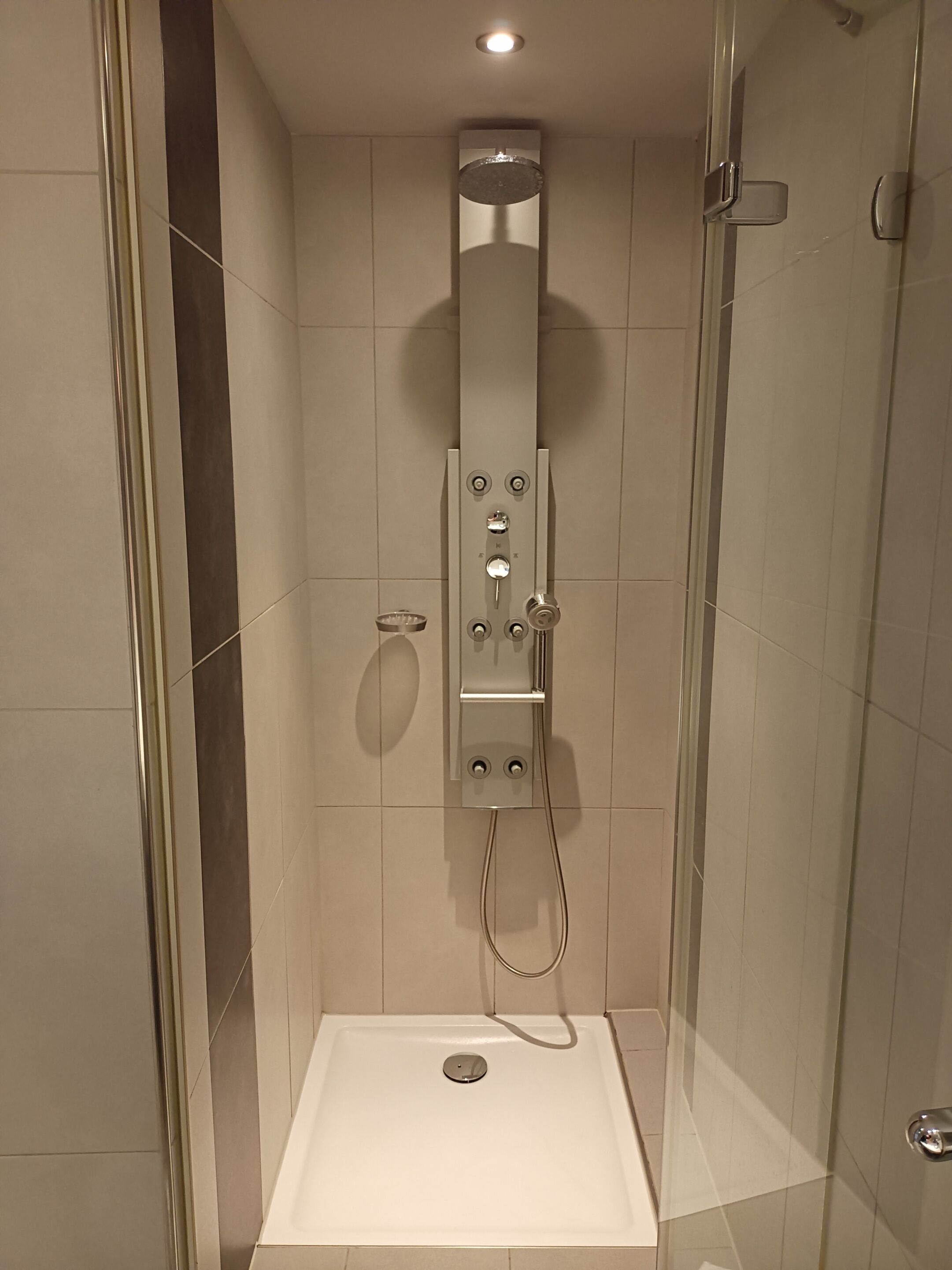 Box de chuveiro moderno com painel de controle, chuveiro manual e ralo.