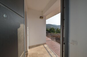 Corredor que leva a uma varanda com vista para montanhas ao longe.