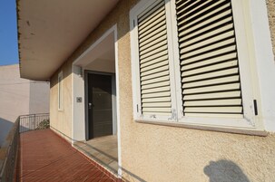 Um edifício com varanda, porta e grades na janela.