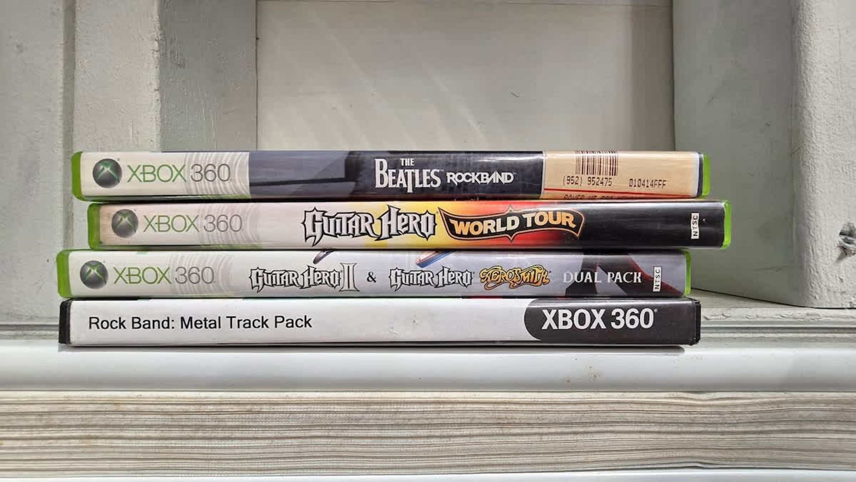 Uma pilha de capas de jogos do Xbox 360 em uma prateleira.