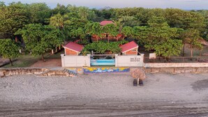 Uma casa de praia com piscina, rodeada por vegetação exuberante.