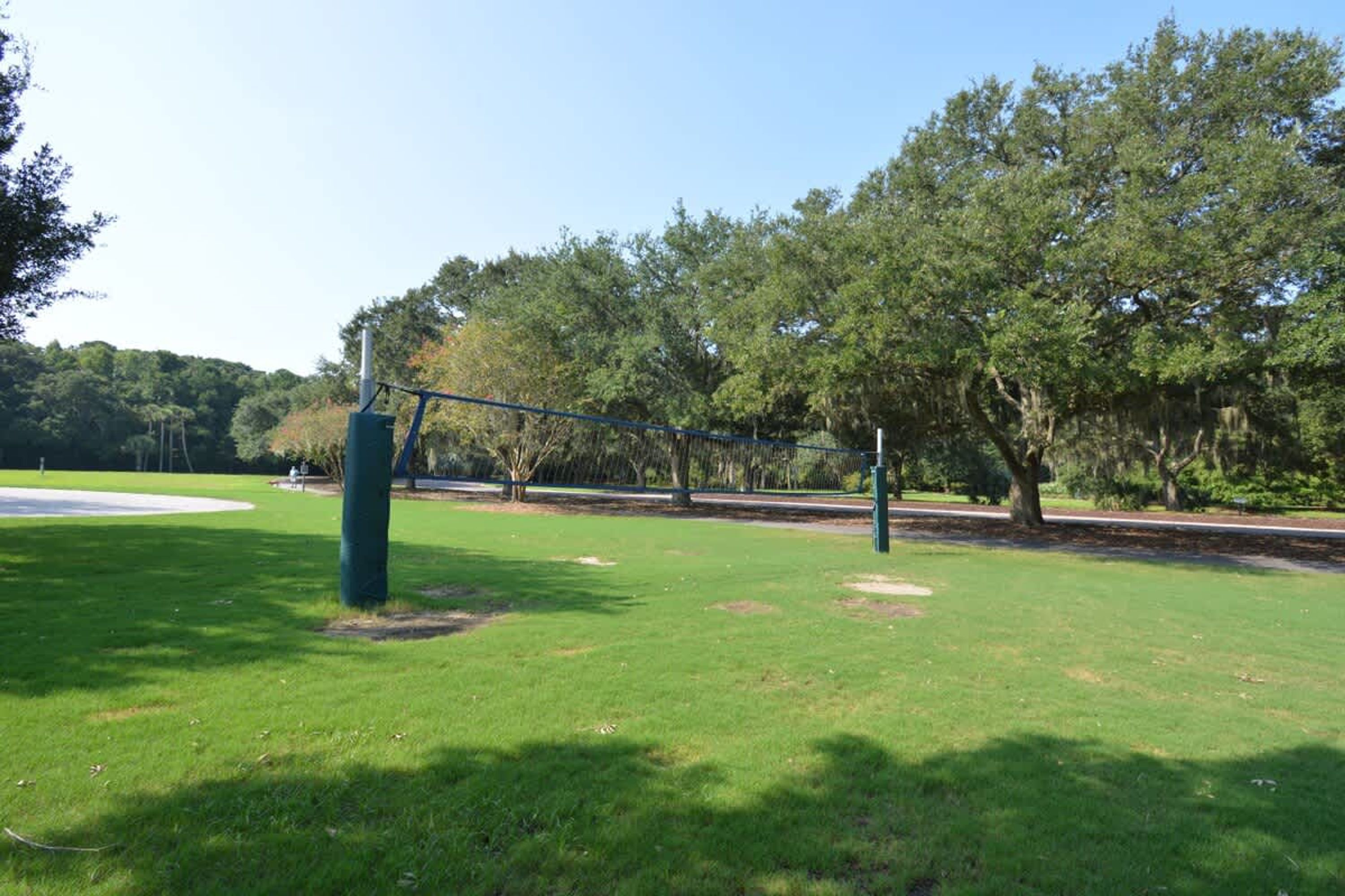 Um parque com baloiço, um mastro verde e uma zona relvada.