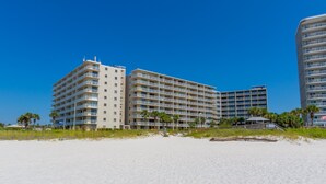 Um hotel à beira-mar com vários andares, varandas e uma praia arenosa em primeiro plano.