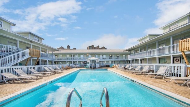 Uma área de piscina com várias espreguiçadeiras e uma piscina central.