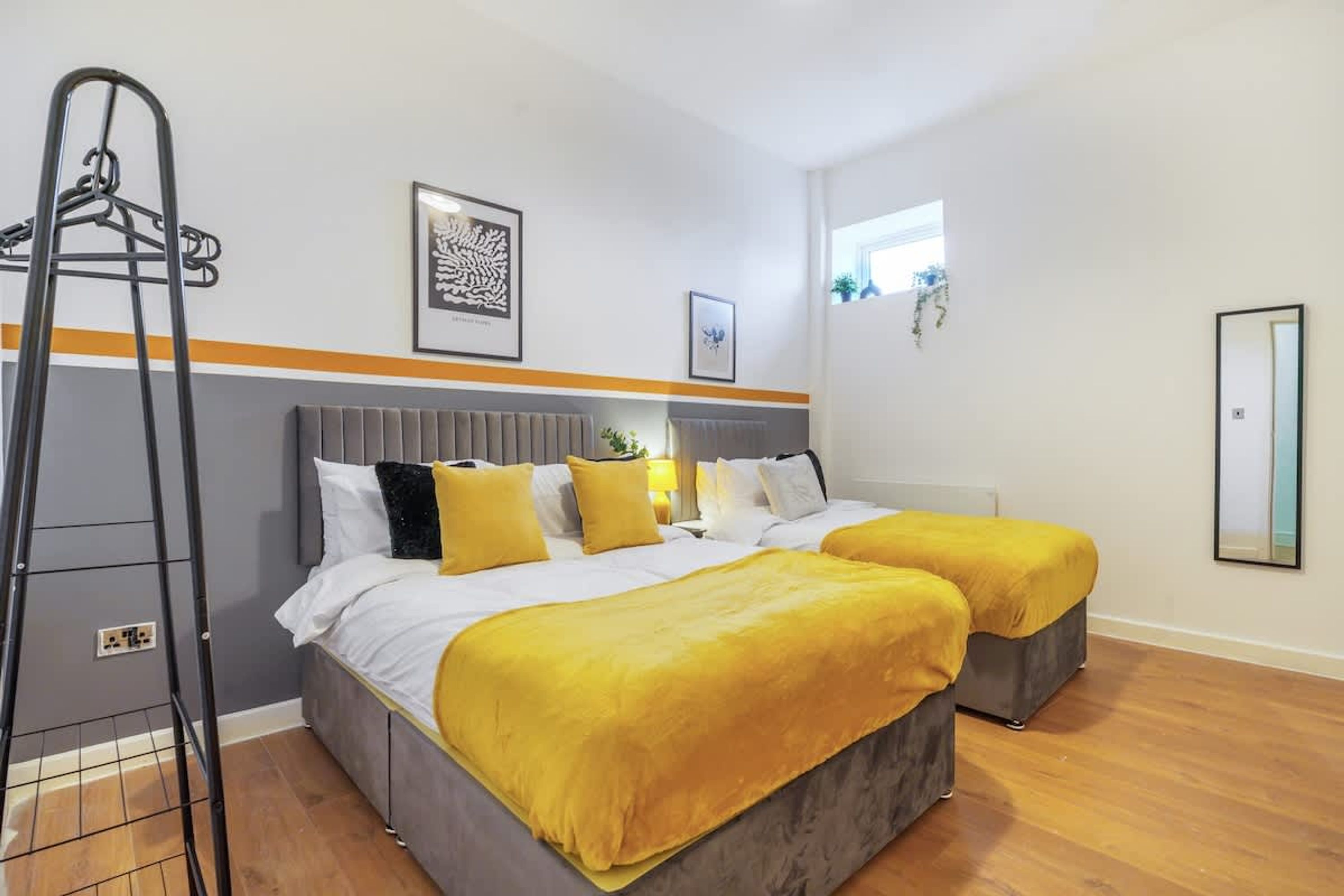 Quarto com cama, duas mesas de cabeceira, luminária pendente e janela.