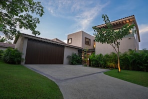 Uma casa moderna com uma garagem ampla, um gramado bem cuidado e um céu claro.