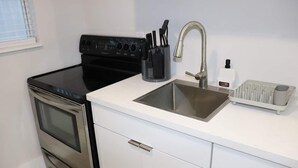 Uma cozinha com fogão de aço inoxidável, pia com torneira moderna e porta-facas.