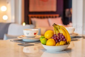Uma tigela de frutas sobre uma mesa, com uma xícara e pires ao fundo.