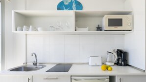 Uma cozinha moderna com armários brancos, pia, torradeira, cafeteira e micro-ondas.