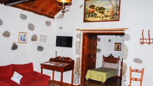 Um quarto acolhedor com um sofá vermelho, uma mesa de madeira, uma cama com colcha verde e um quadro na parede.