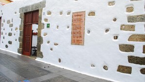 Um edifício branco com fachada de pedra, porta de madeira e uma placa na parede.