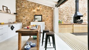 Cozinha moderna com parede de pedra, mesa de madeira e banquetas de bar.