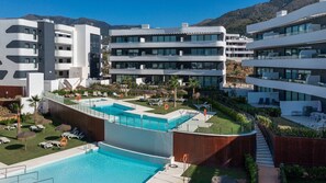 Um hotel moderno com área de piscina, várias varandas e vista para as montanhas.