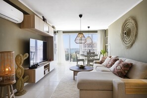 Sala moderna com televisão de tela plana, sofá, mesa de jantar e varanda com vista.