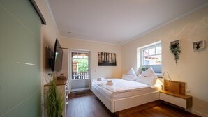 Quarto com cama, mesa de cabeceira, luminária e um vaso com planta.