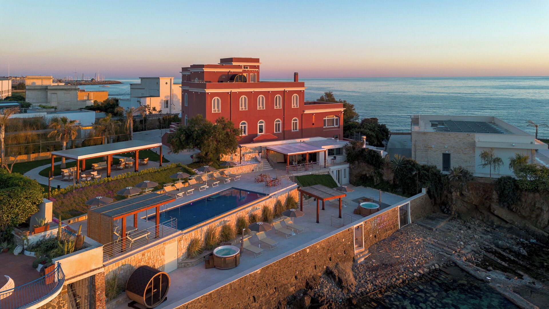 Um edifício grande com piscina, área de estar externa e vista para o mar.