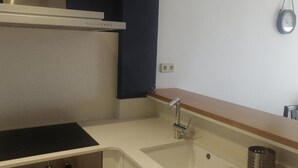Cozinha com fogão, pia e bancada de madeira.
