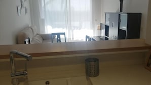 Cozinha moderna com pia de aço inoxidável, lixeira e bancada de madeira.