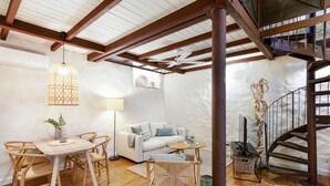 Uma sala de estar acolhedora com uma mesa de madeira, cadeiras, um sofá e uma escada.