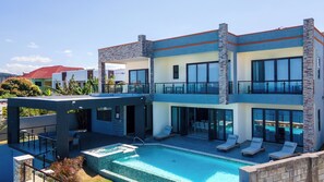Uma casa moderna de dois andares com piscina, área de estar externa e varanda.
