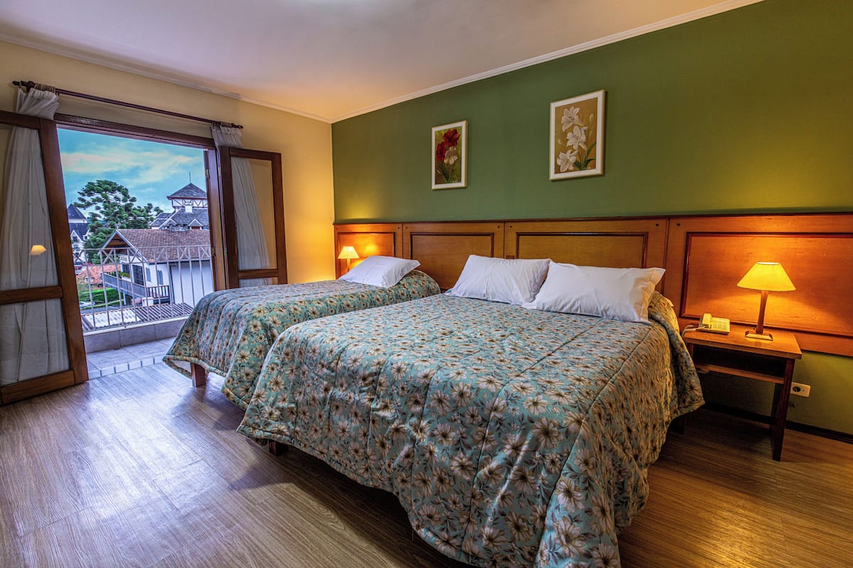 Quarto duplo com duas camas, varanda e vista para edifícios.
